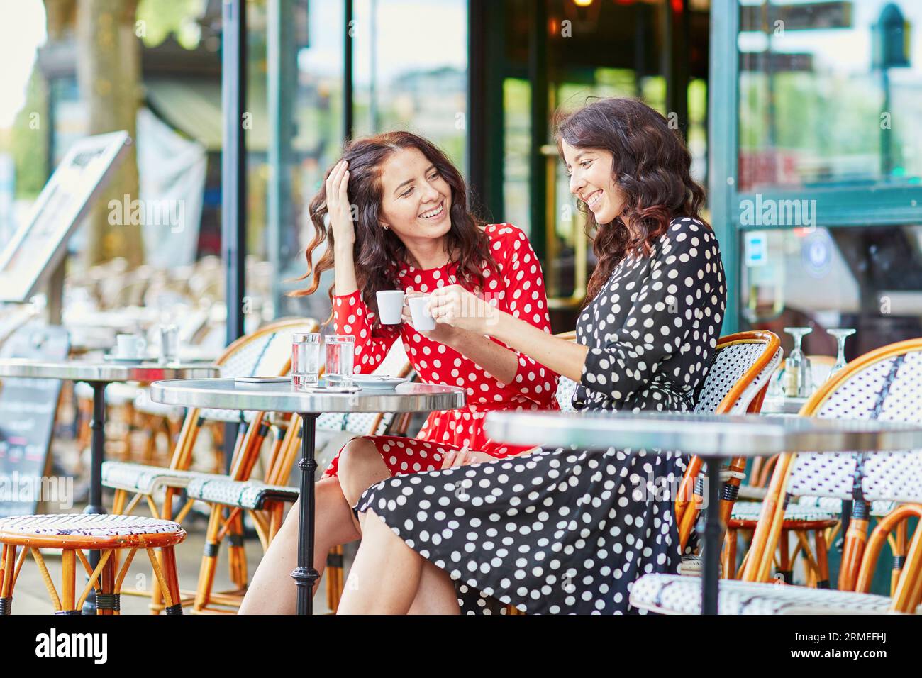 Beautiful twin sisters drinking coffee in a cozy outdoor cafe in Paris ...