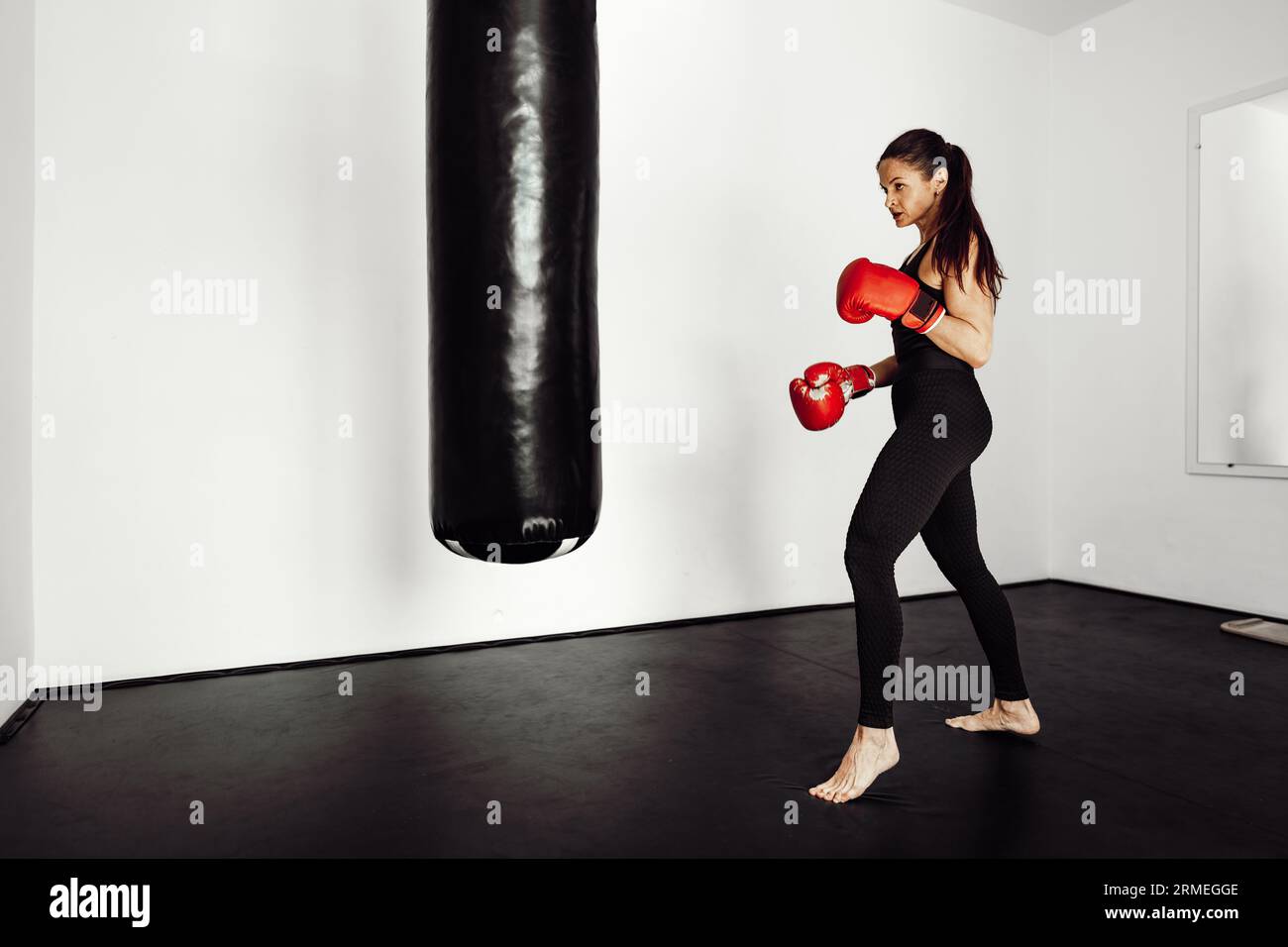 Woman athlete in red boxing gloves hits a pear in a gym Stock Photo - Alamy