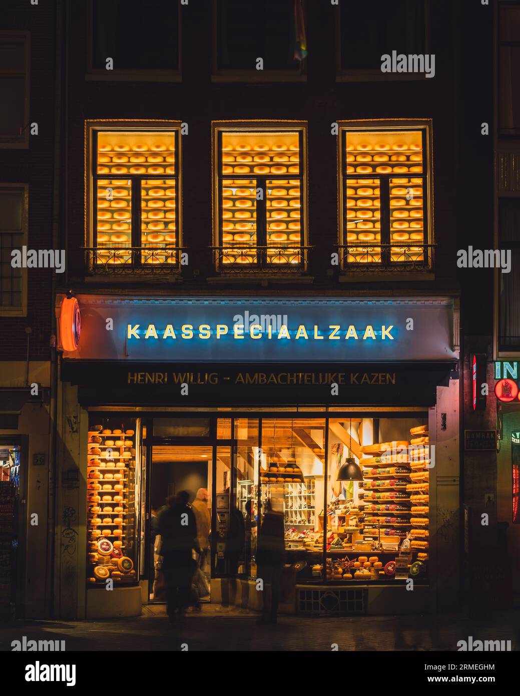 A cheese shop in Amsterdam at night. Big yellow cheese rounds lit up in ...