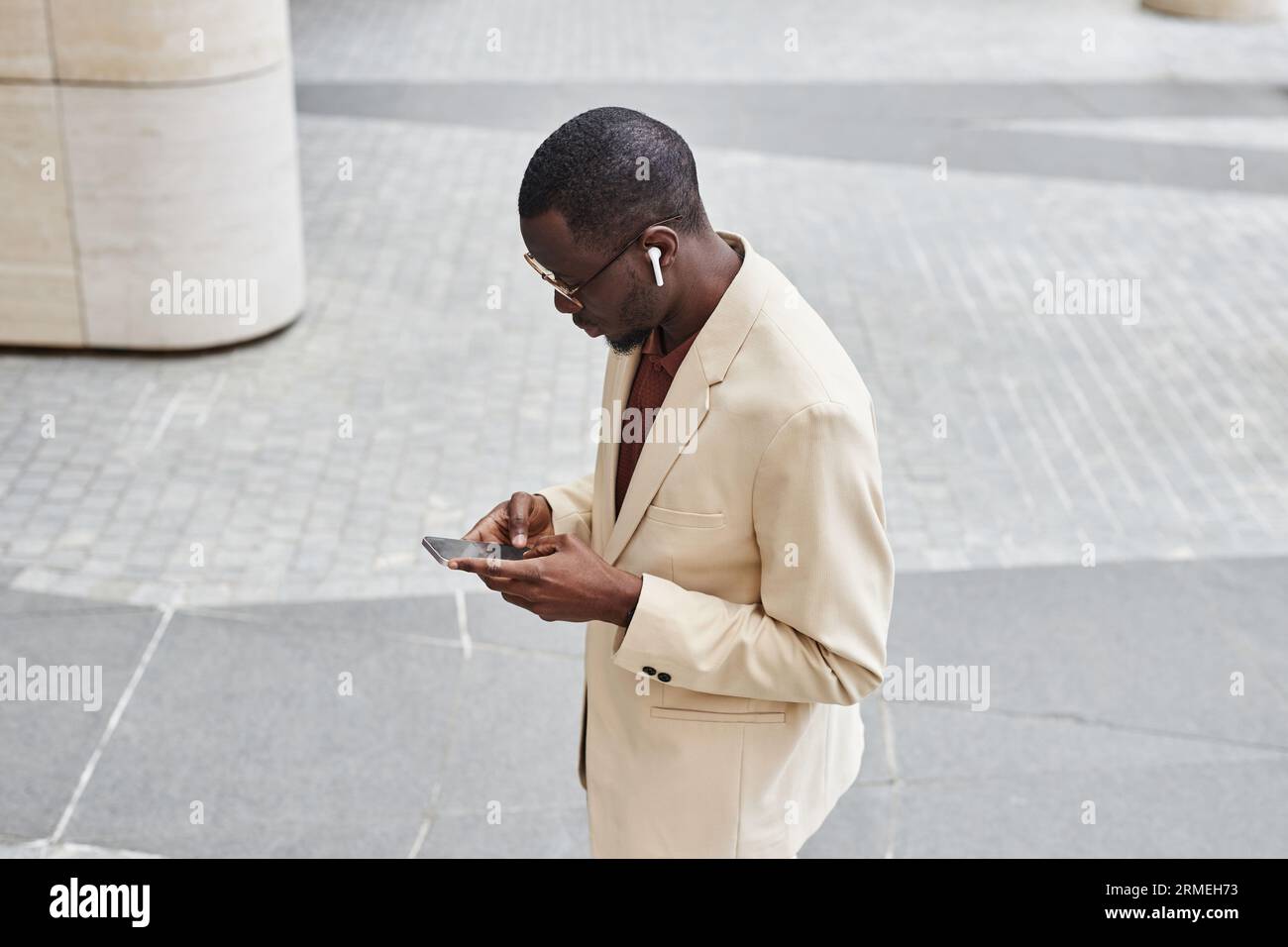 High angle of young black businessman in earphones and pastel color ...