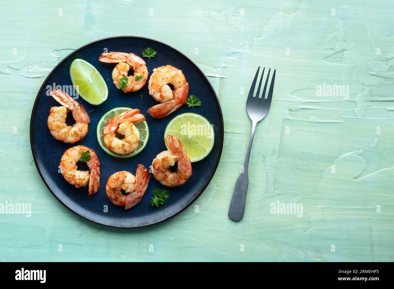 Shrimps, top shot. Cooked shrimp with limes, shot from above on a teal ...