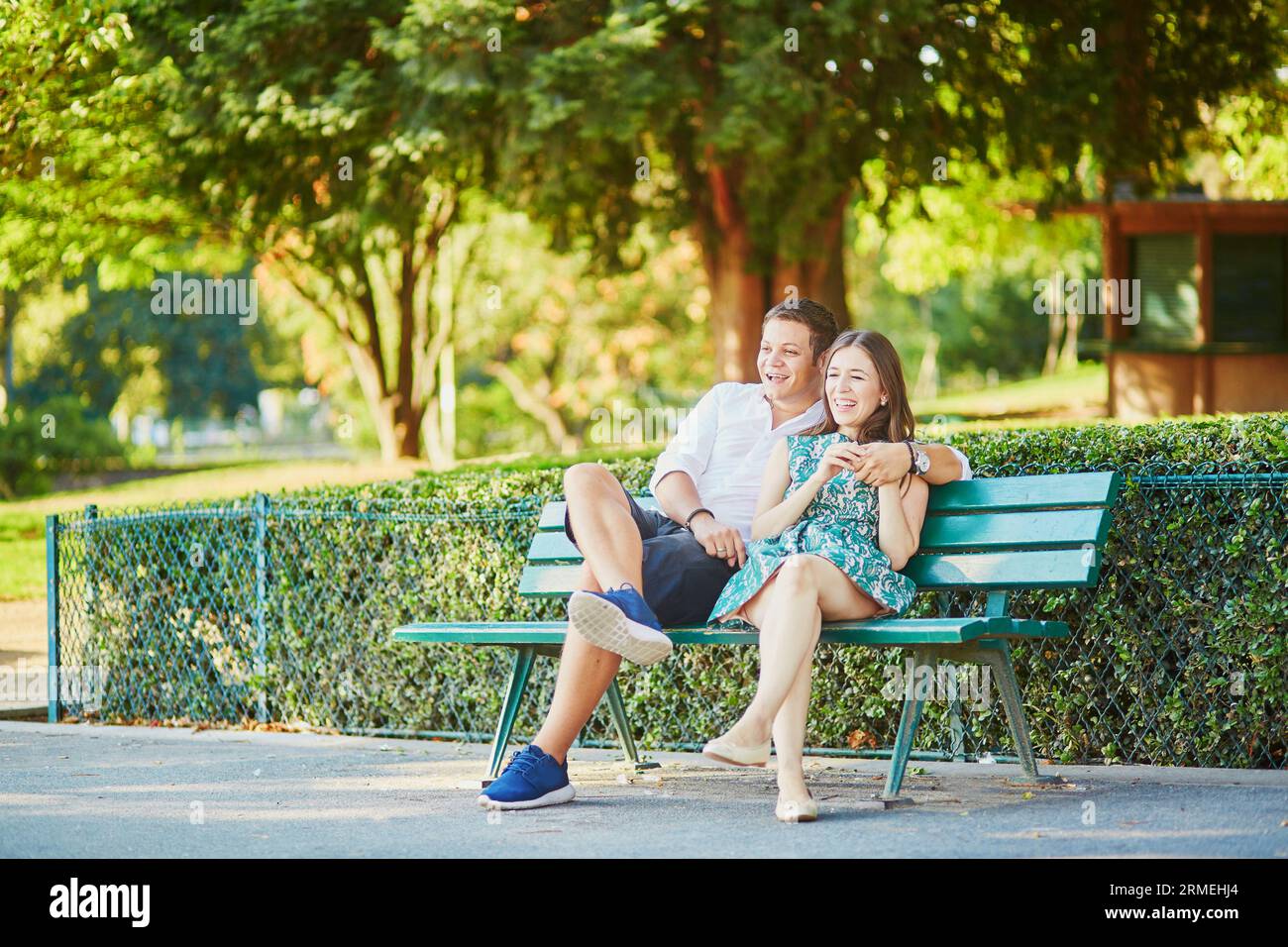 Happy dating couple hugging on a bench in a Parisian park near the Eiffel tower Stock Photo - Alamy