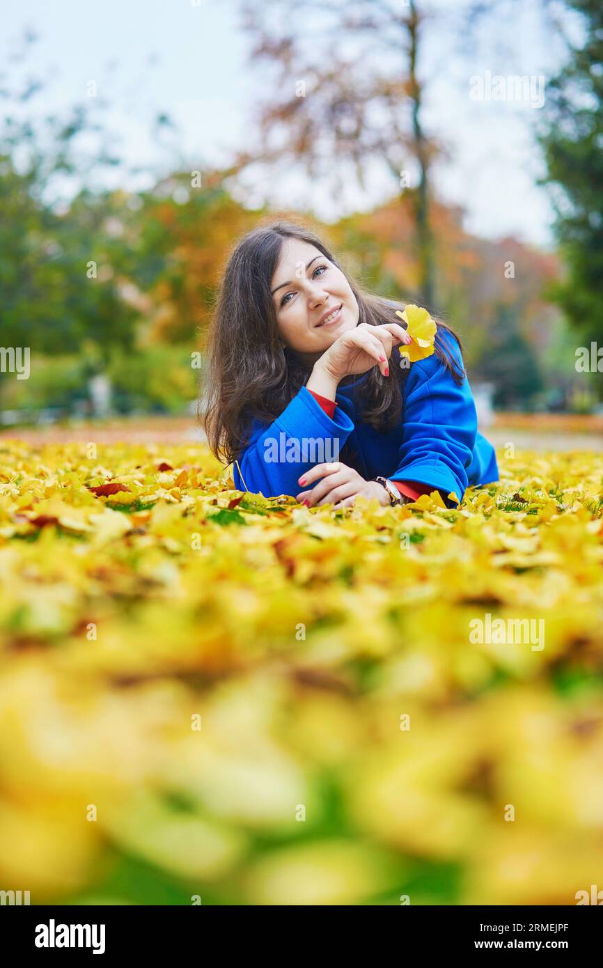 Beautiful young woman on a fall day, laying on the ground with colorful ...