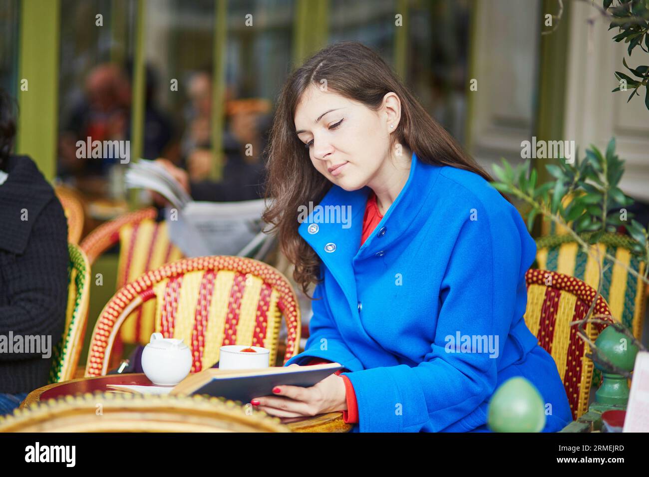 Beautiful young Parisian girl reading a book in cafe Stock Photo - Alamy
