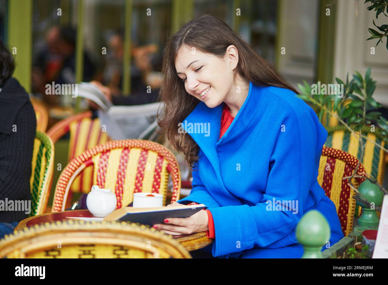 Beautiful young Parisian girl reading a book in cafe Stock Photo - Alamy