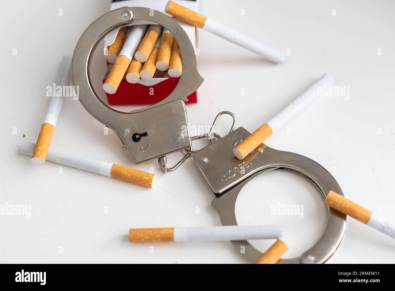 Bunch of cigarettes in the handcuffs on the white floor. No Tobacco day ...