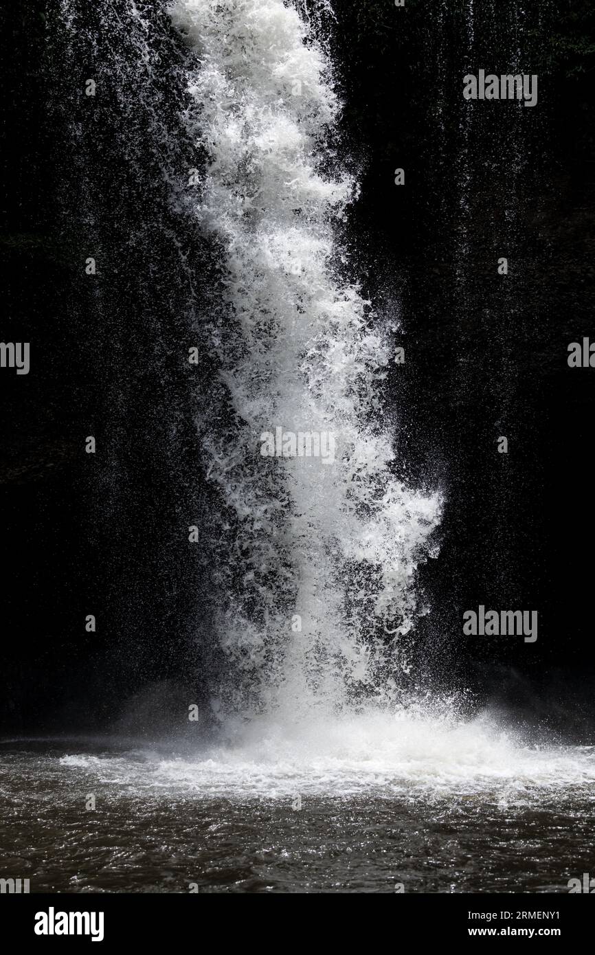 Splashing water from powerful waterfall with dark background of cave ...