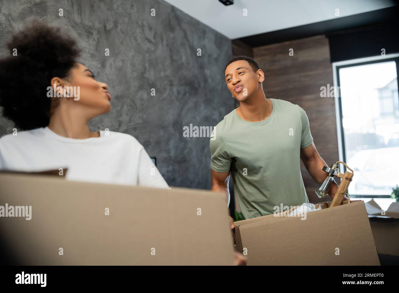 african american couple pouting lips while holding carton packages ...