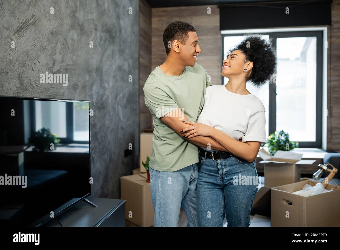happy african american man hugging girlfriend near blurred cardboard ...