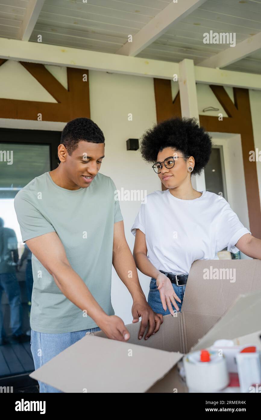 african american woman pointing at carton box near boyfriend during ...