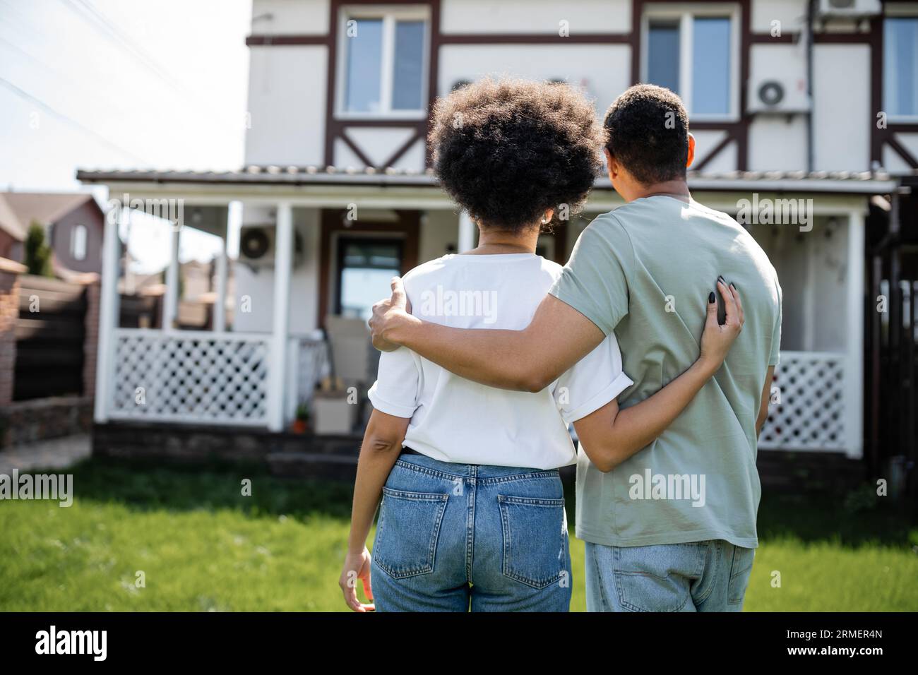 back view of african american couple hugging while standing near new ...