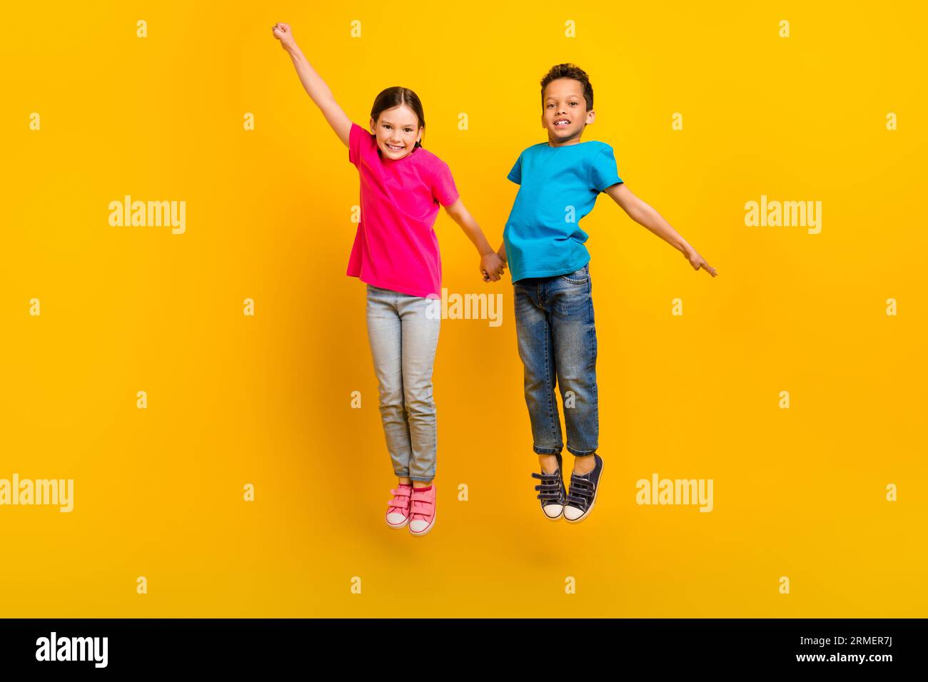 Full size photo of two active excited fellows kids jumping hold arms ...