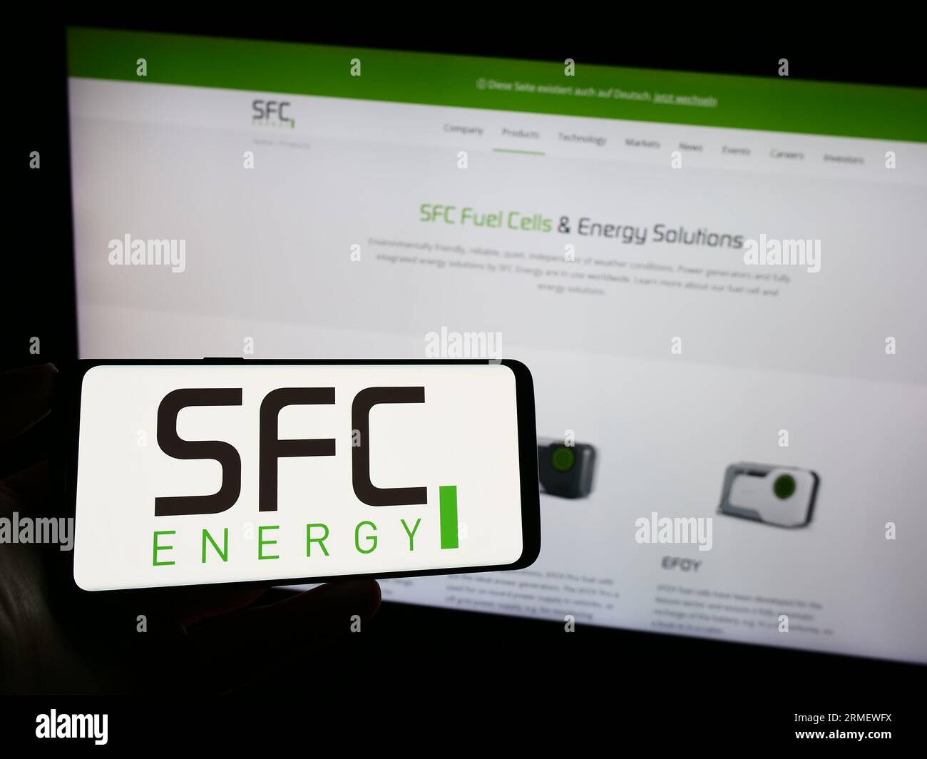 Person holding mobile phone with logo of German company SFC Energy AG ...