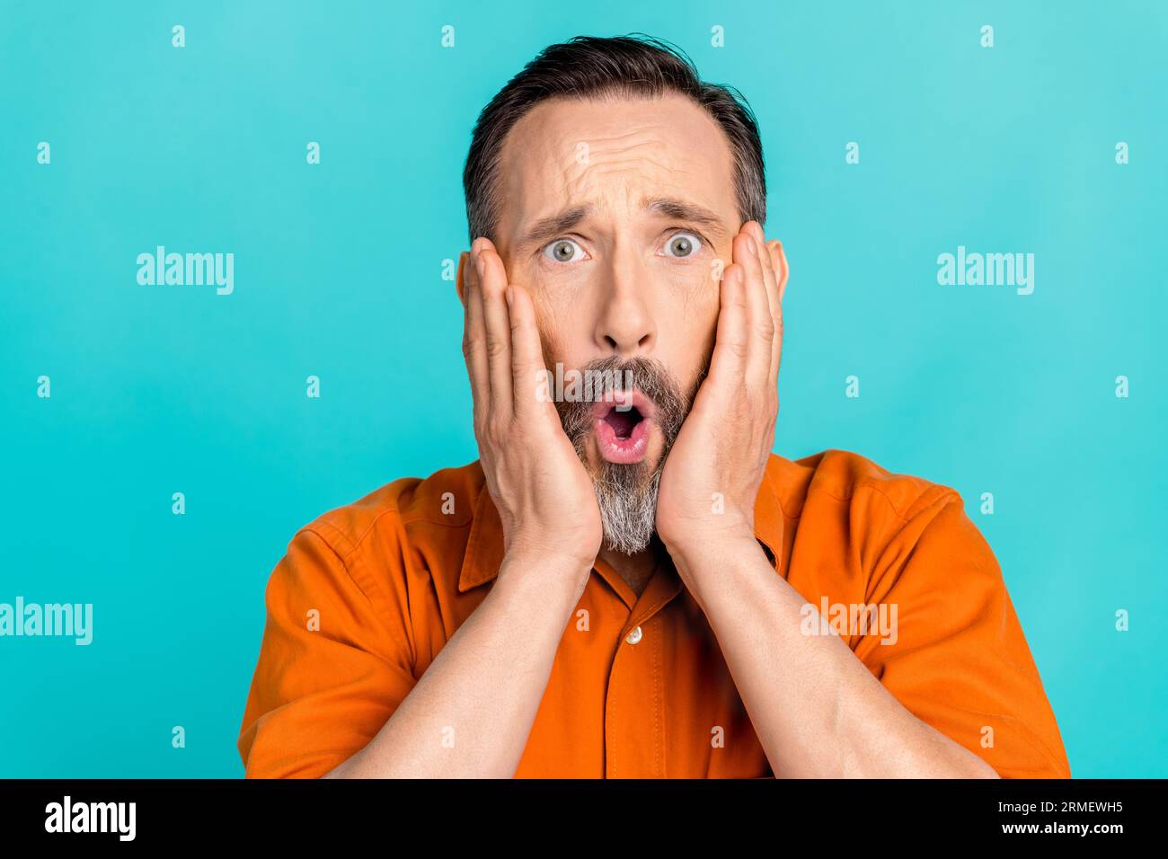 Photo of funny astonished staring questioned man retired hands cheeks ...