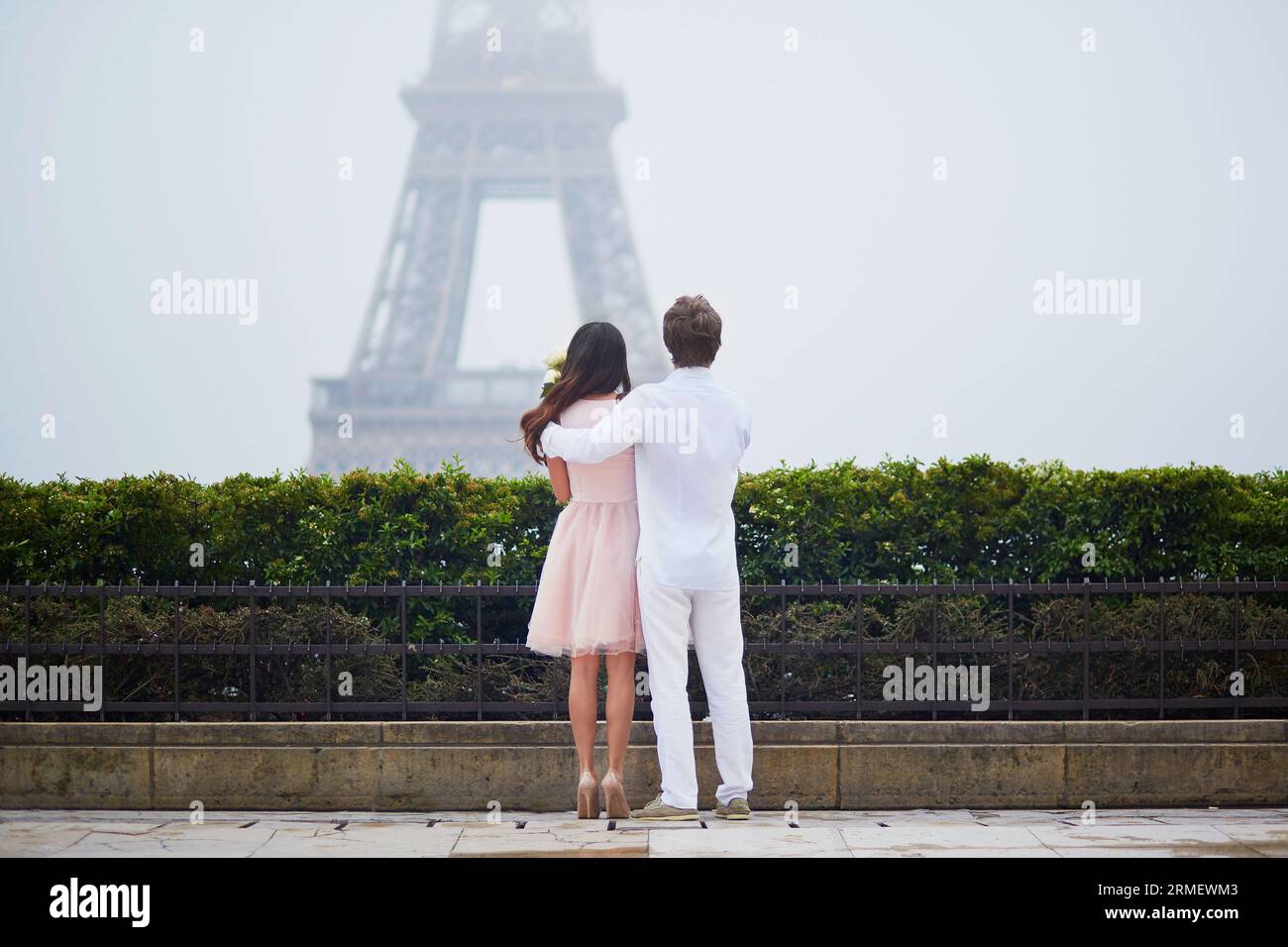Beautiful romantic couple in love looking at the Eiffel tower in Paris ...
