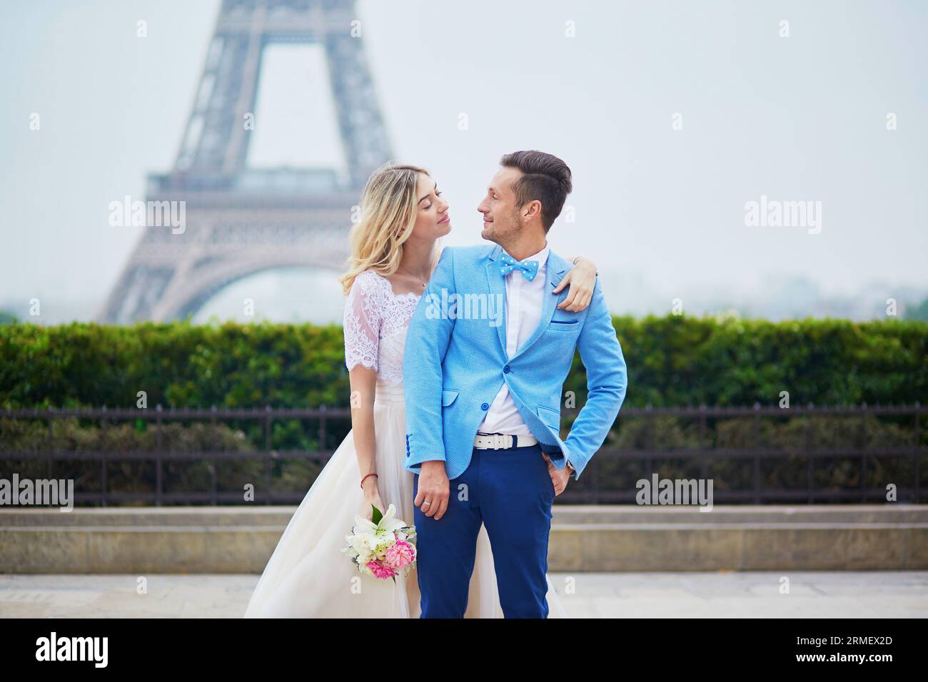 Just married couple near the Eiffel tower on their wedding day. Bride ...