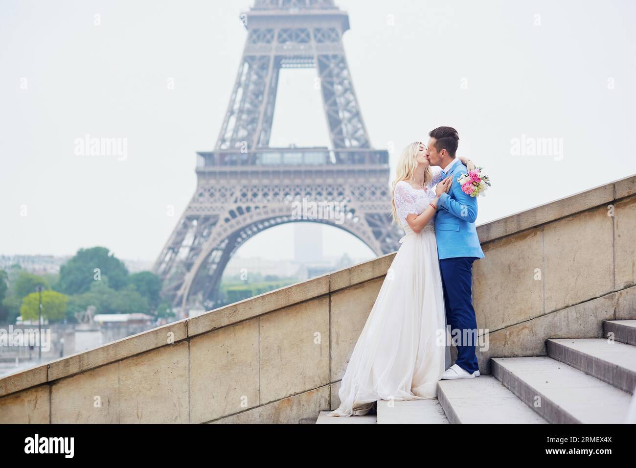 Just married couple near the Eiffel tower on their wedding day. Bride ...