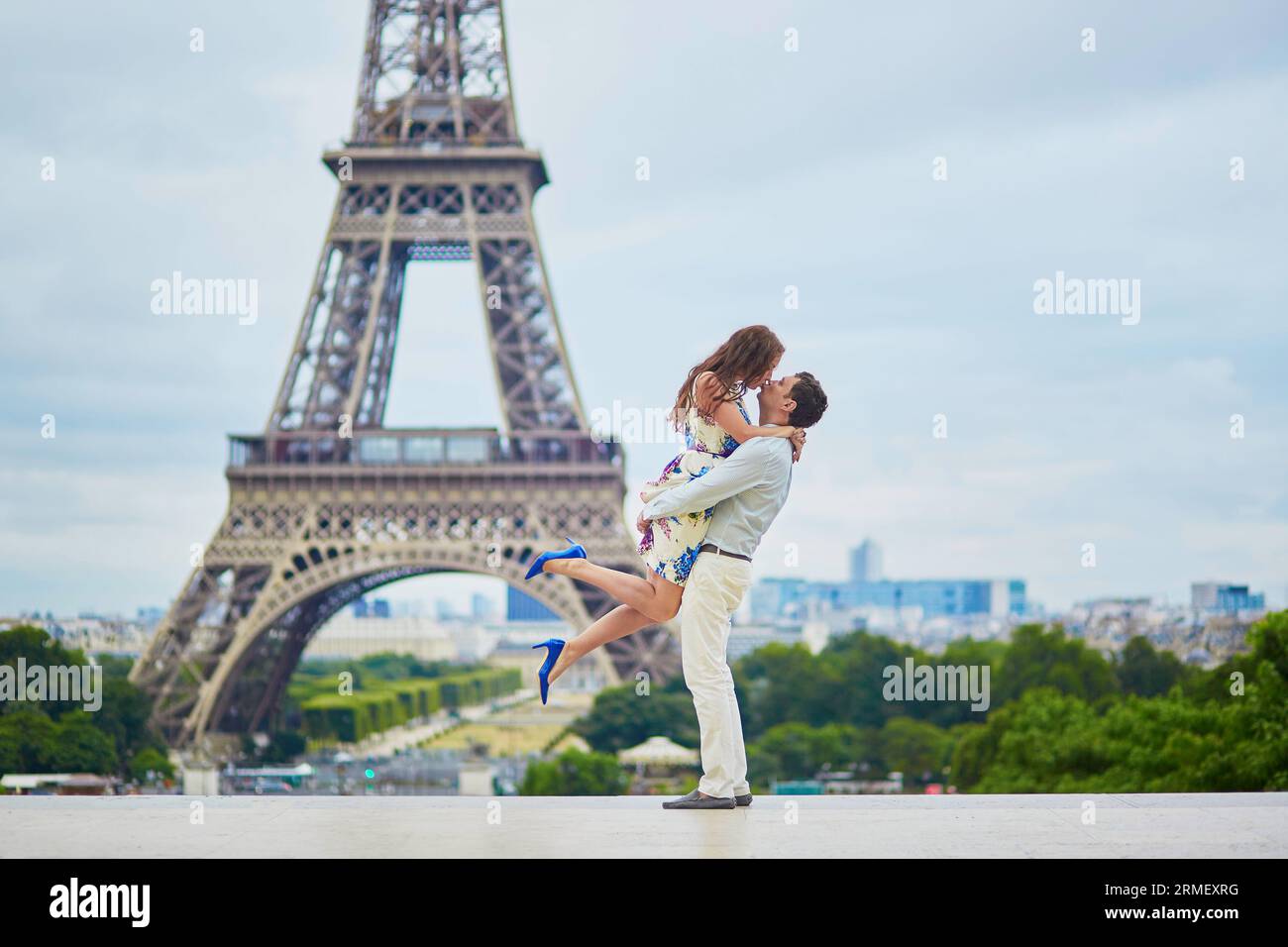 Loving couple having a date near the Eiffel tower. Romantic jump hug ...