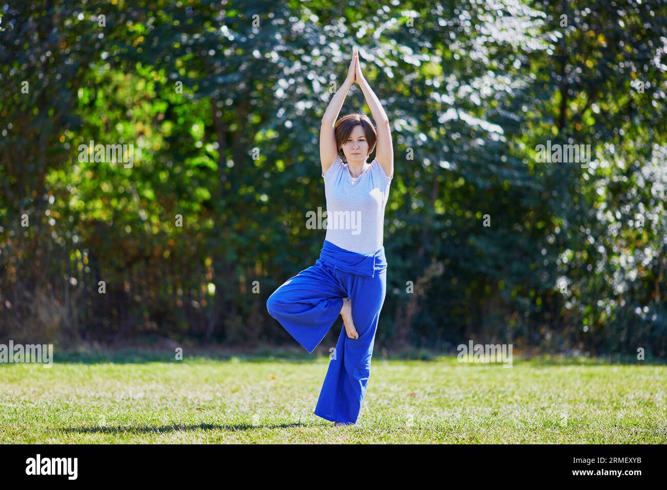 Young woman doing yoga outdoors in tranquil environment. Performing ...