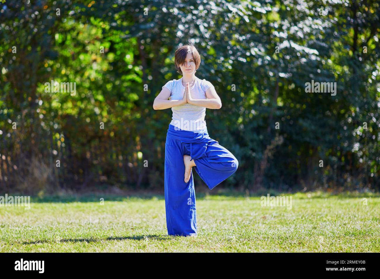 Young woman doing yoga outdoors in tranquil environment. Performing ...