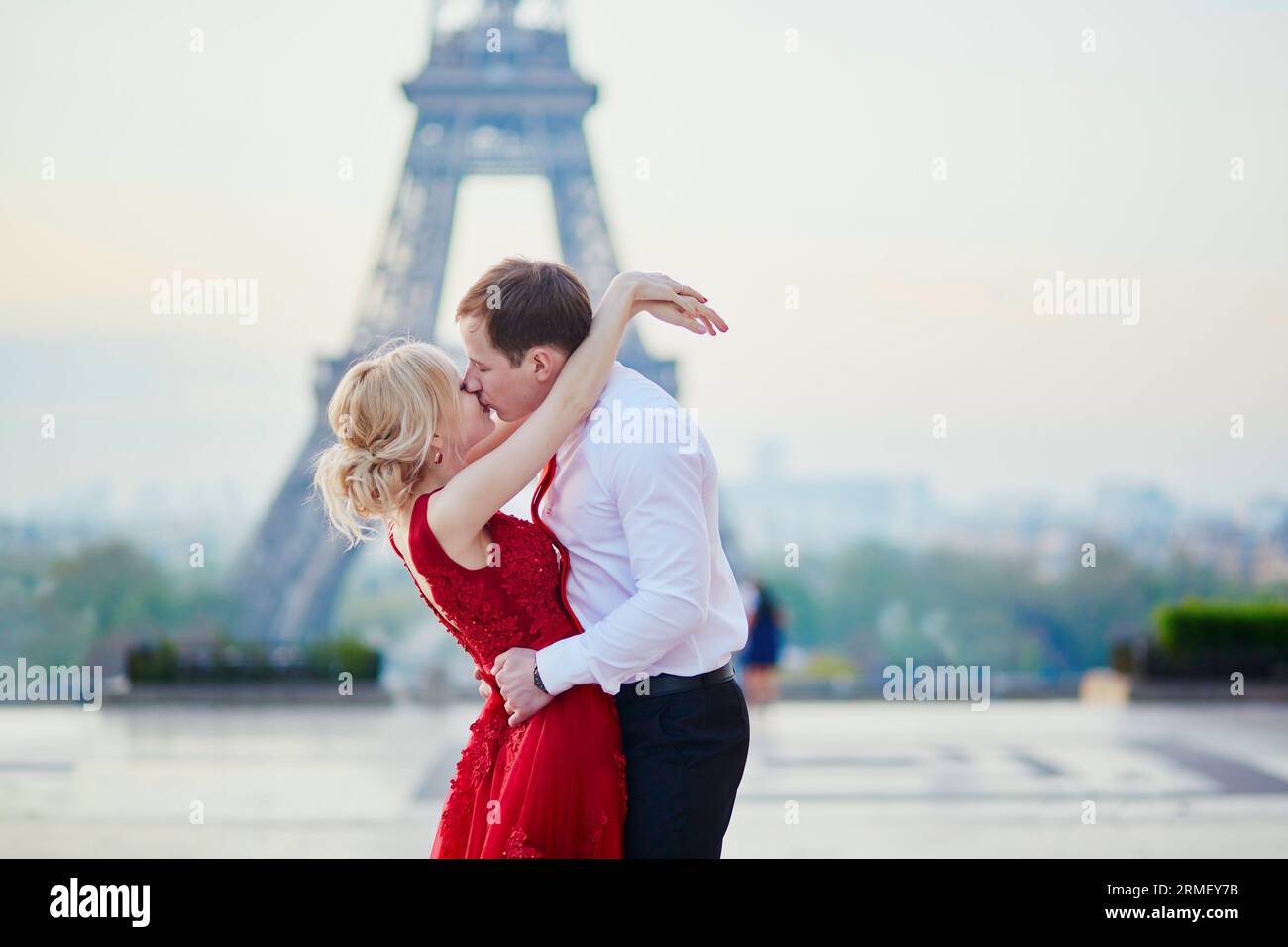 Beautiful romantic couple kissing in front of the Eiffel tower in Paris ...