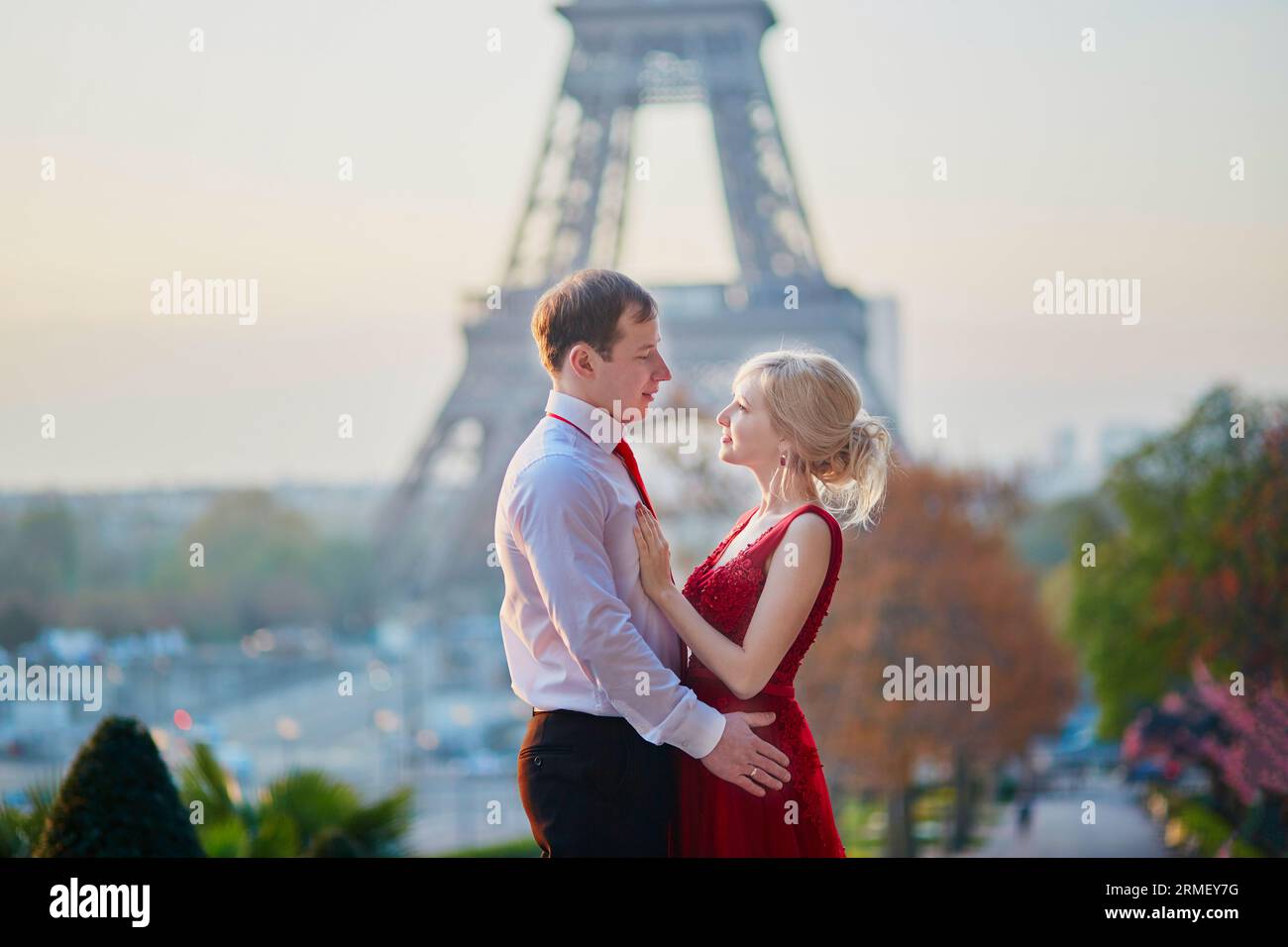 Beautiful romantic couple in love hugging in front of the Eiffel tower ...