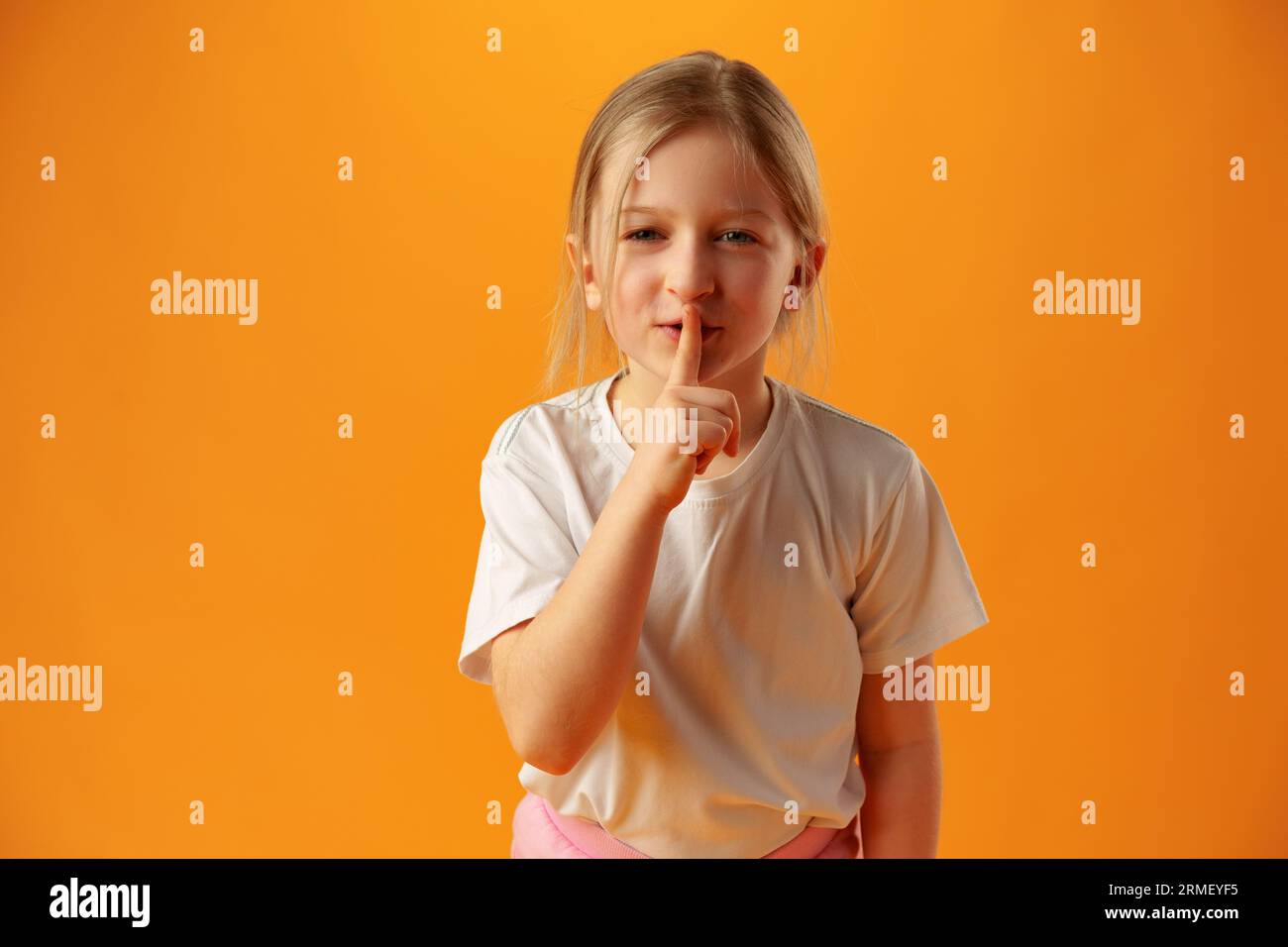 Little girl showing silence gesture against yellow background Stock ...