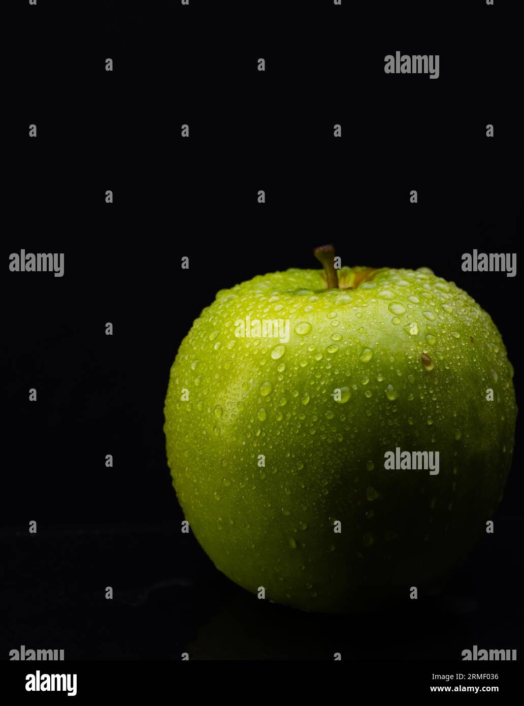 Micro close up of green apple with water drops and copy space on black ...