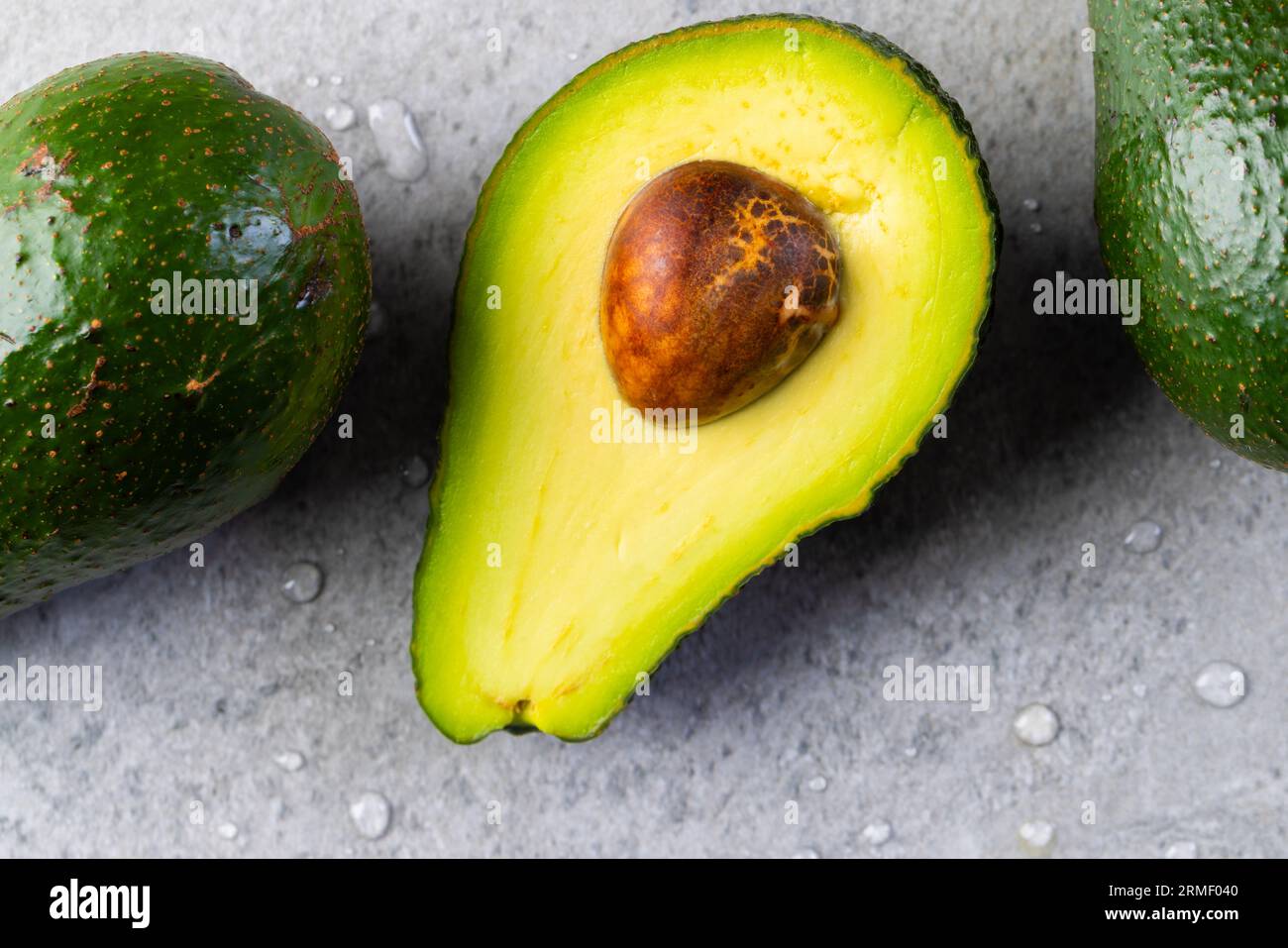 Micro close up of avocados with water drops and copy space on grey ...