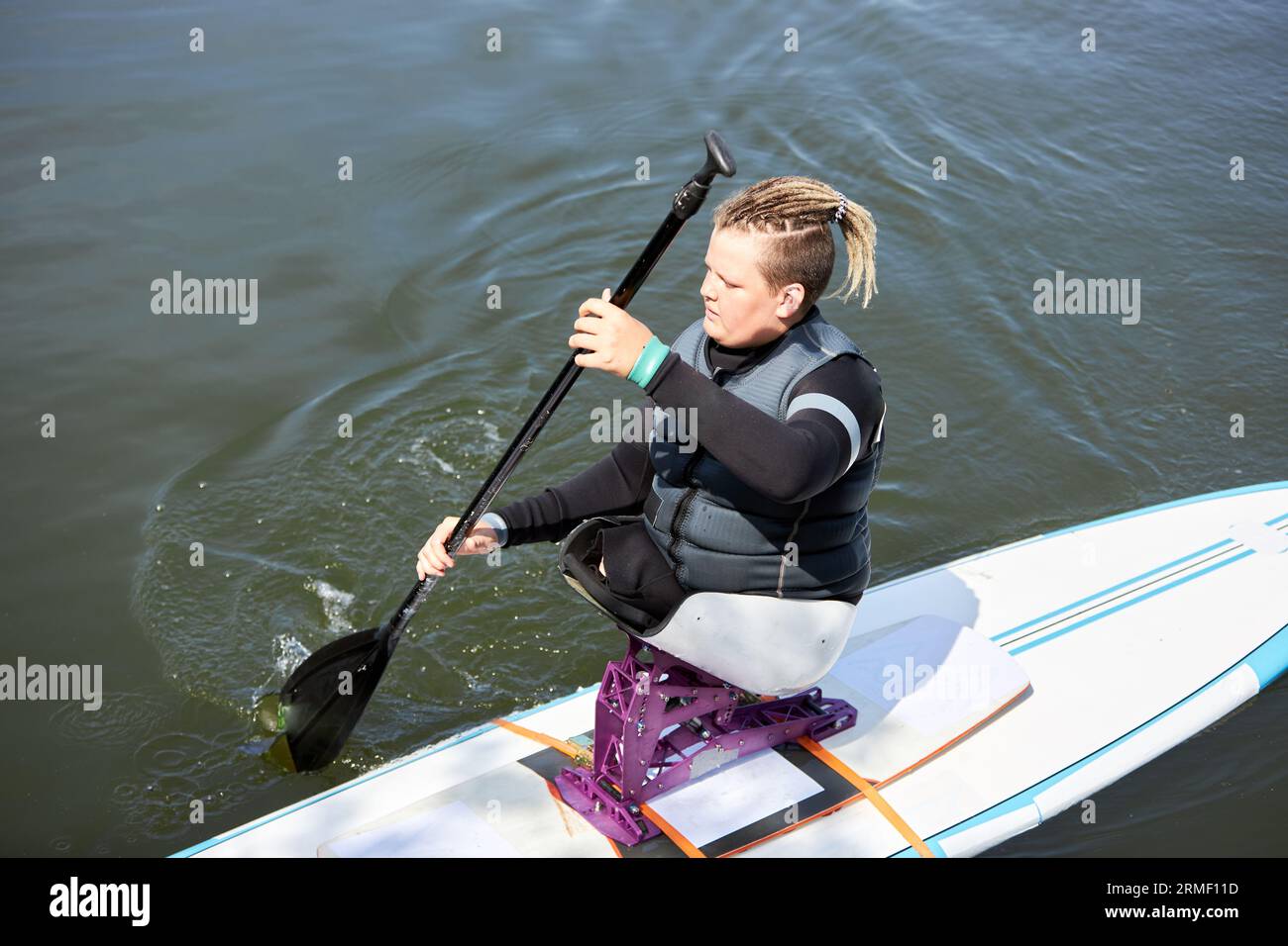 High angle portrait of boy with disability enjoying SUP boarding on ...