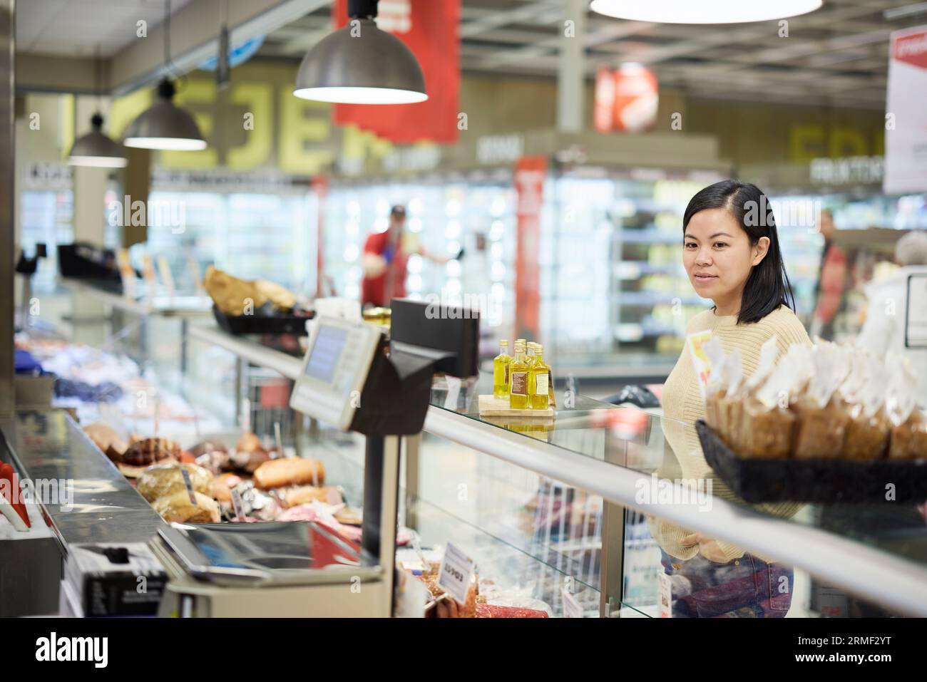 Female customer standing in front of deli counter in supermarket and ...