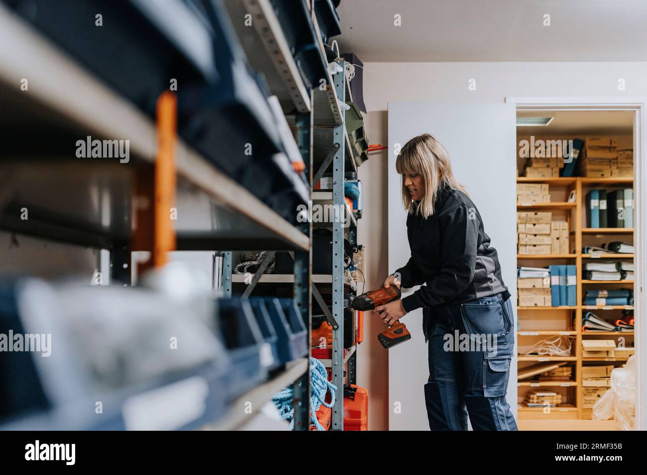 Female worker taking equipment from shelf Stock Photo - Alamy