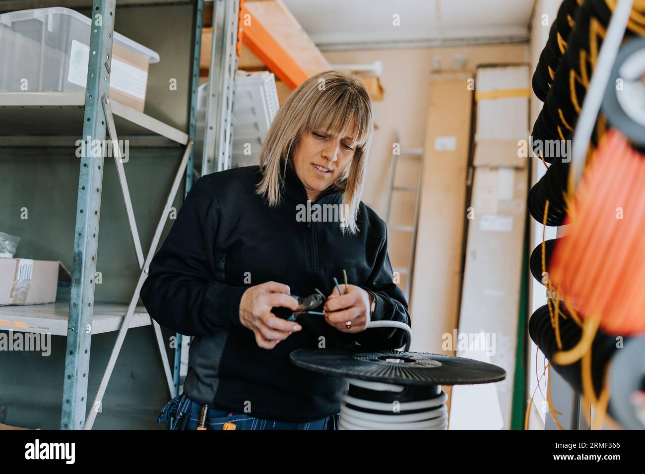 Female electrician cutting cable at work Stock Photo - Alamy