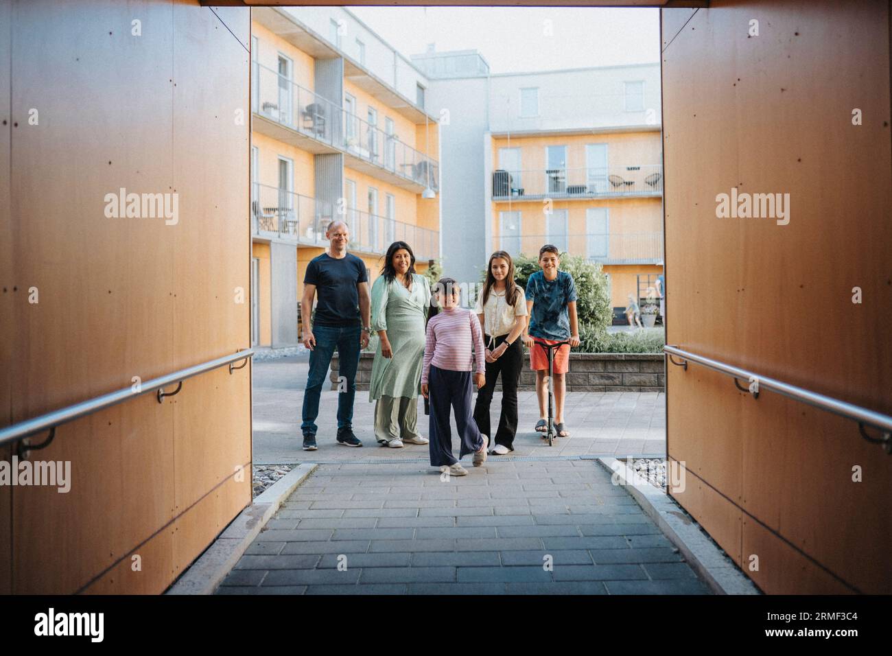 Portrait of family standing in courtyard of residential neighborhood ...