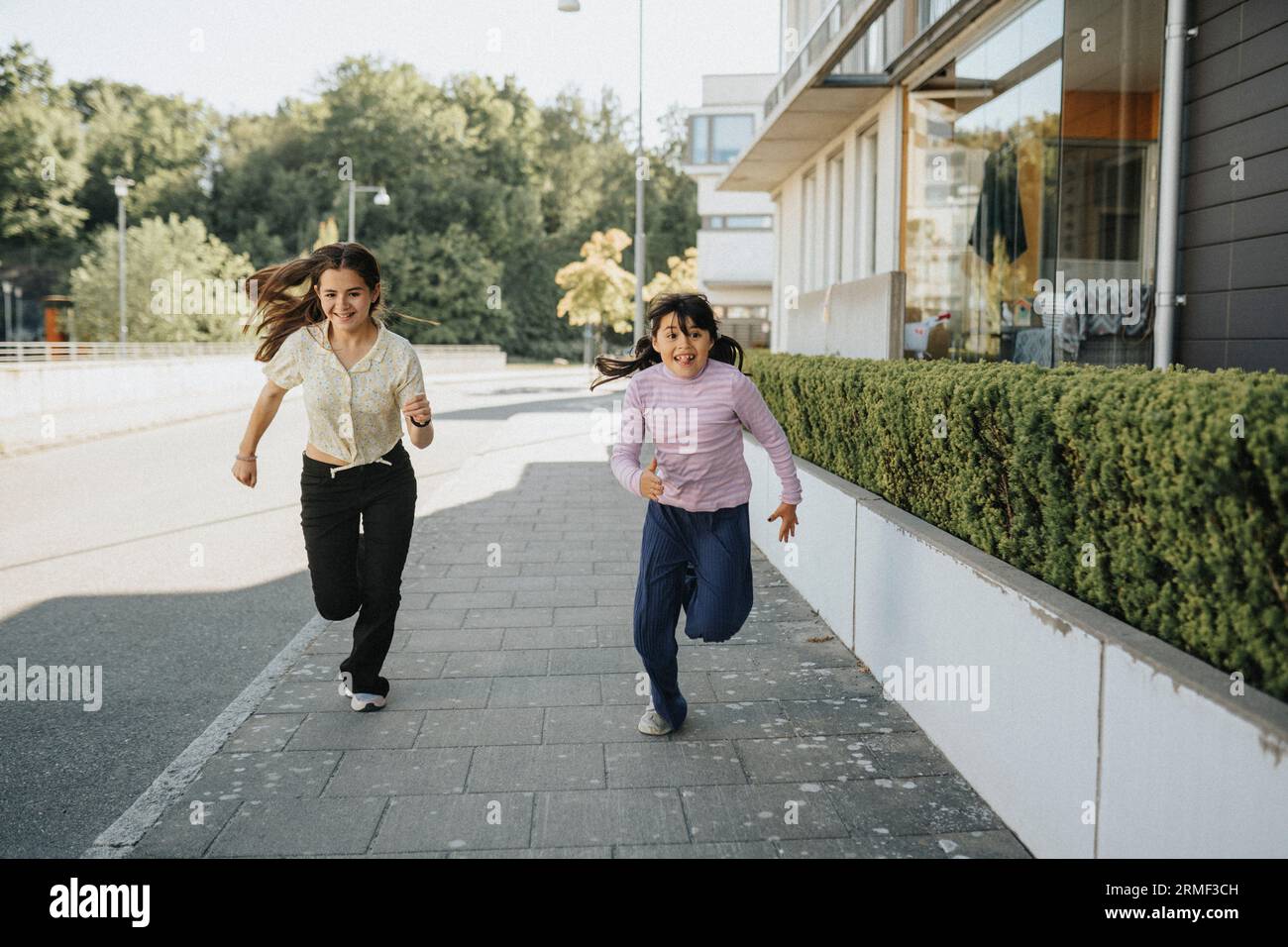 Happy sisters racing down sidewalk Stock Photo - Alamy