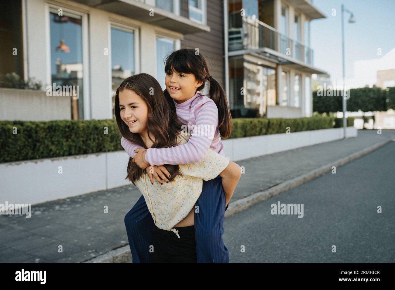 Sisters having fun and giving each other piggyback ride Stock Photo - Alamy