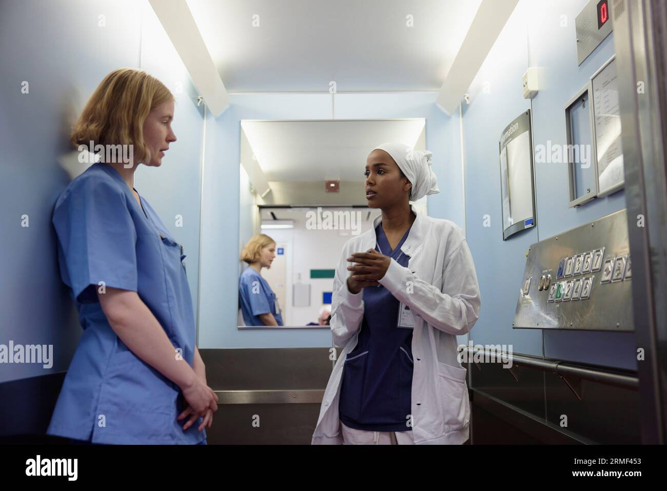 Female doctors taking to each other inside lift in hospital Stock Photo ...