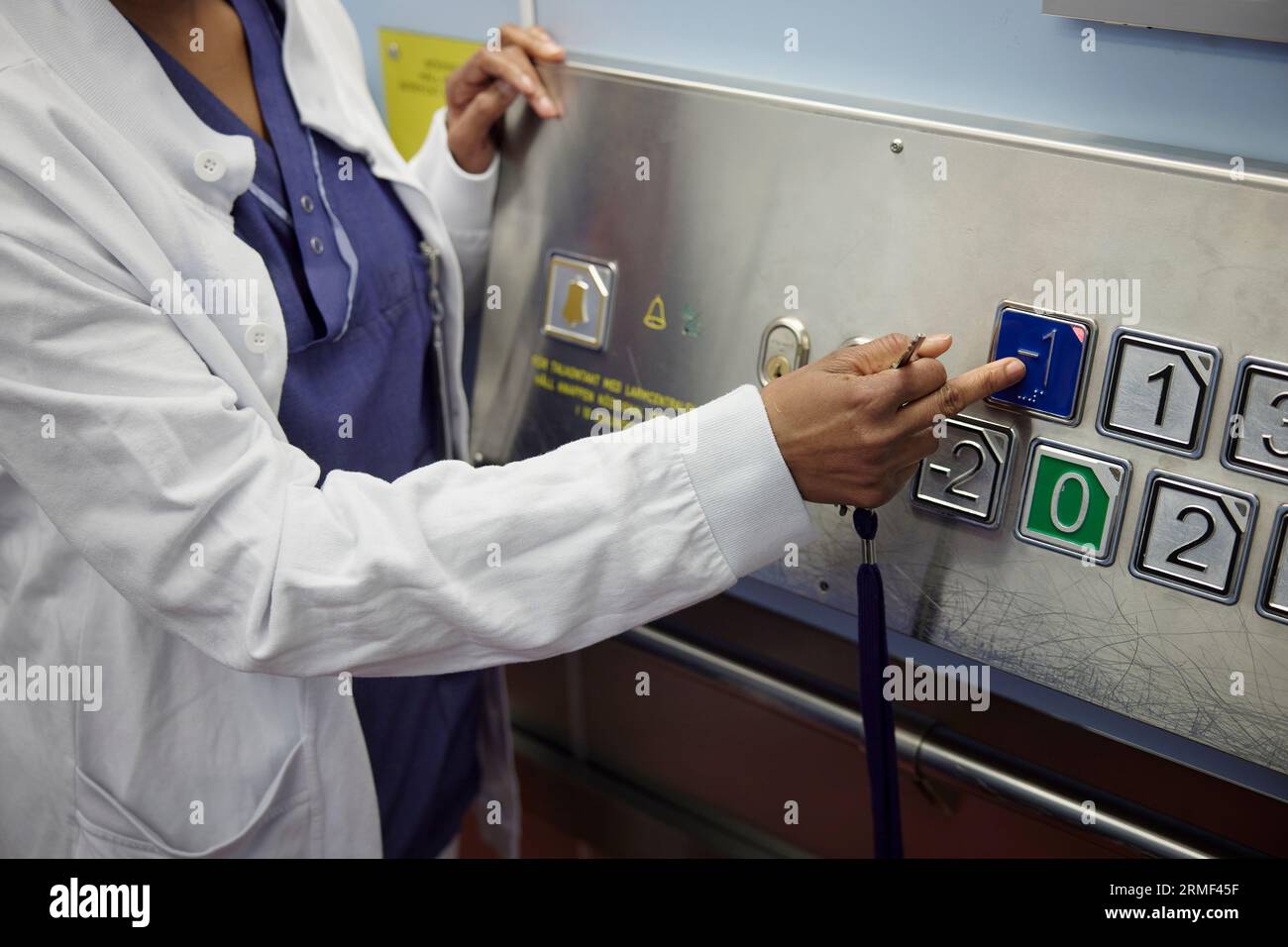 Mid section of female doctor pressing lift button Stock Photo - Alamy