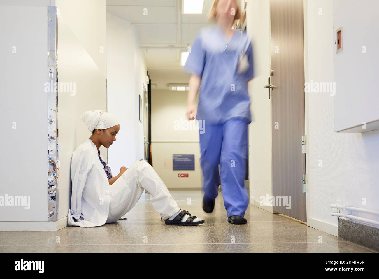 Female doctor sitting on hospital corridor floor Stock Photo - Alamy