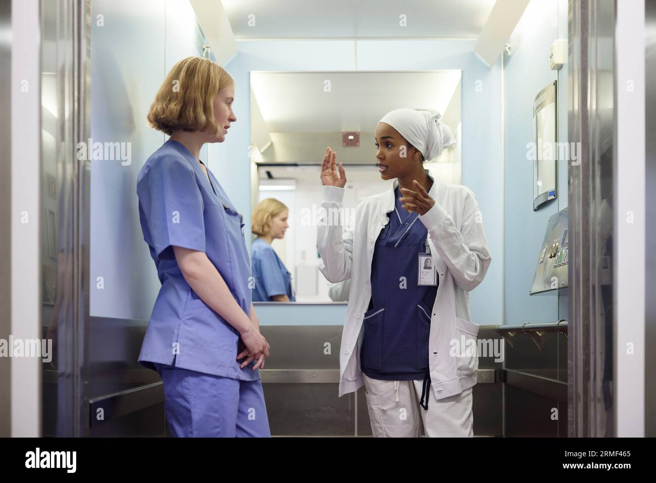 Female doctors taking to each other inside lift in hospital Stock Photo ...