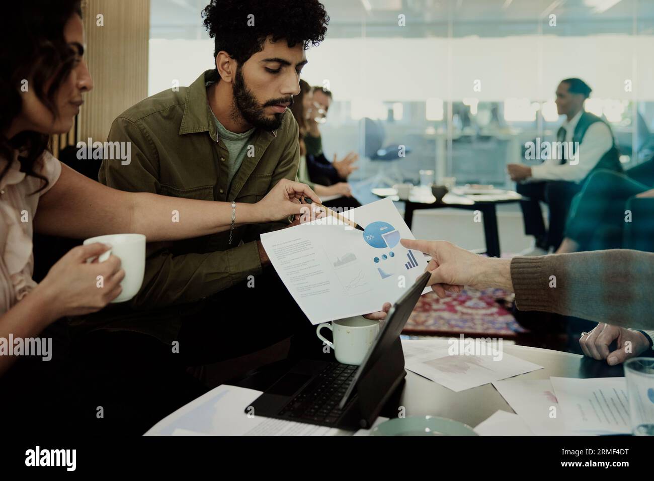 Group of business people analyzing charts during meeting in lobby Stock ...