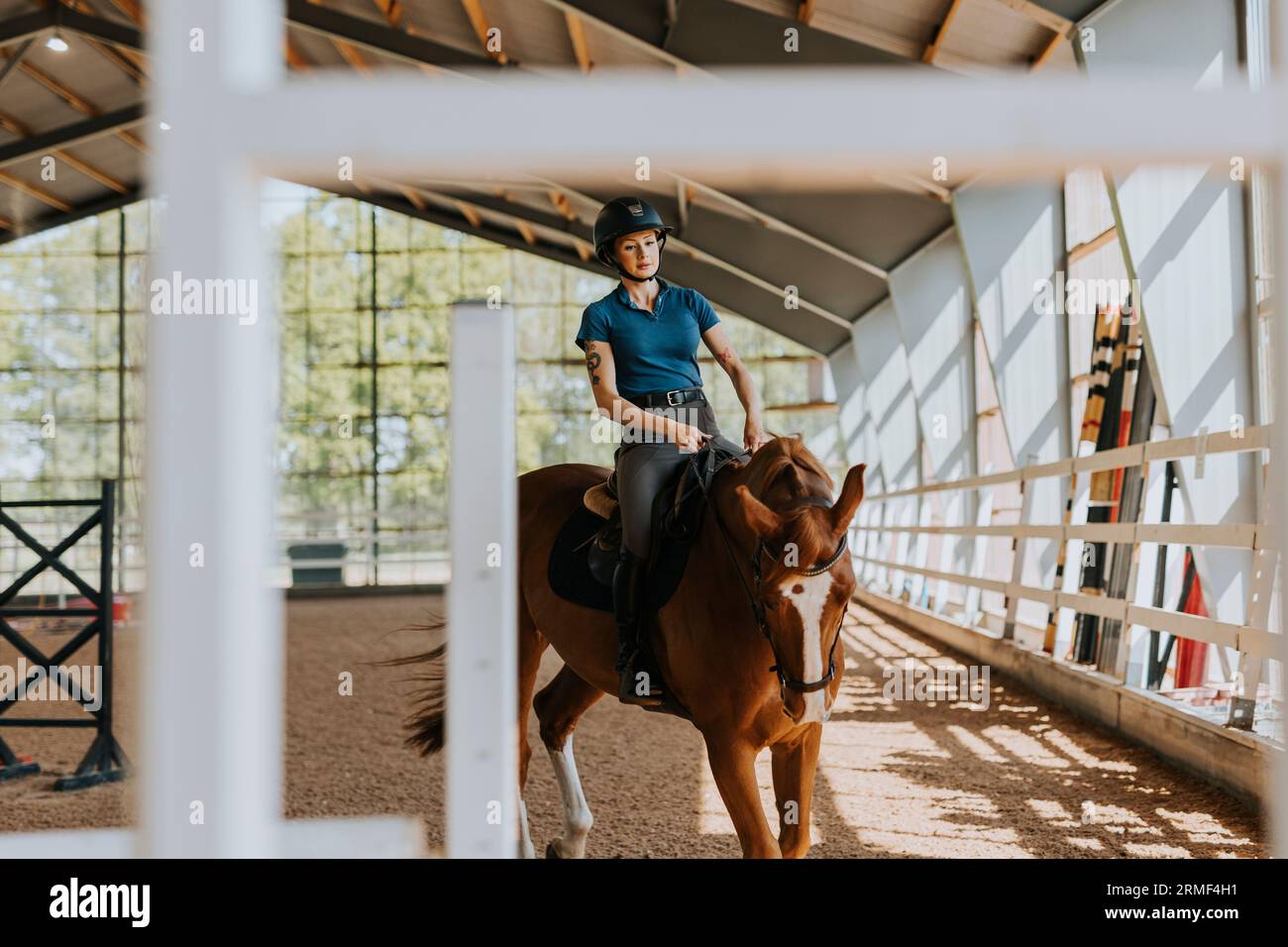 View of female horse rider using indoor riding paddock Stock Photo - Alamy