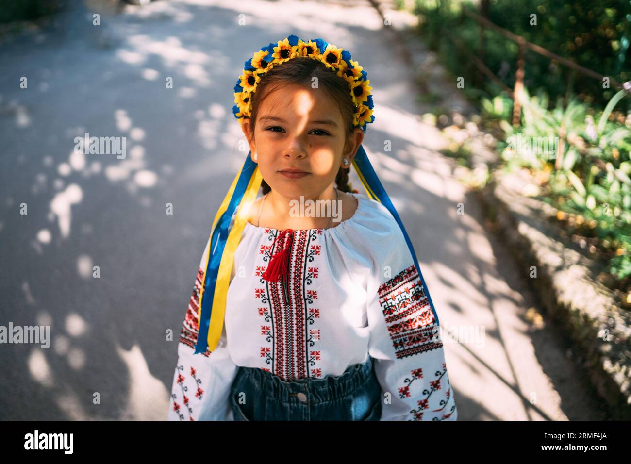 Child girl in Ukrainian traditional clothes and flower wreath is ...