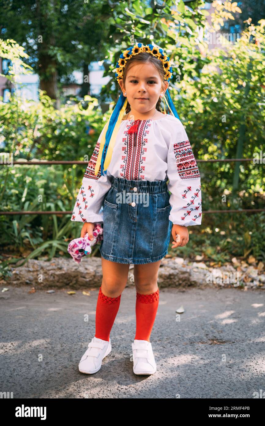 Child girl in Ukrainian traditional clothes and flower wreath is ...