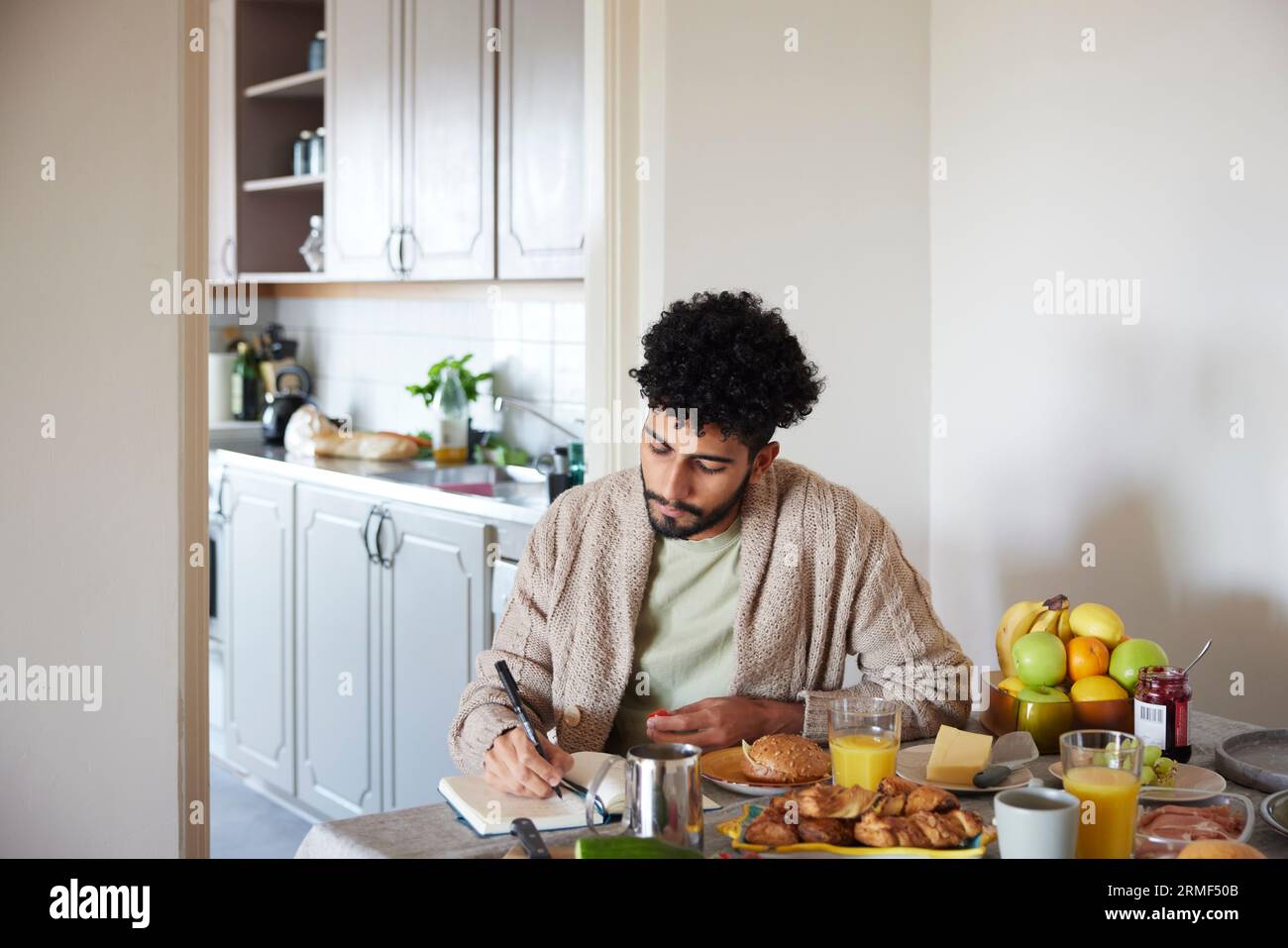 Young man eating breakfast and writing in planner Stock Photo - Alamy