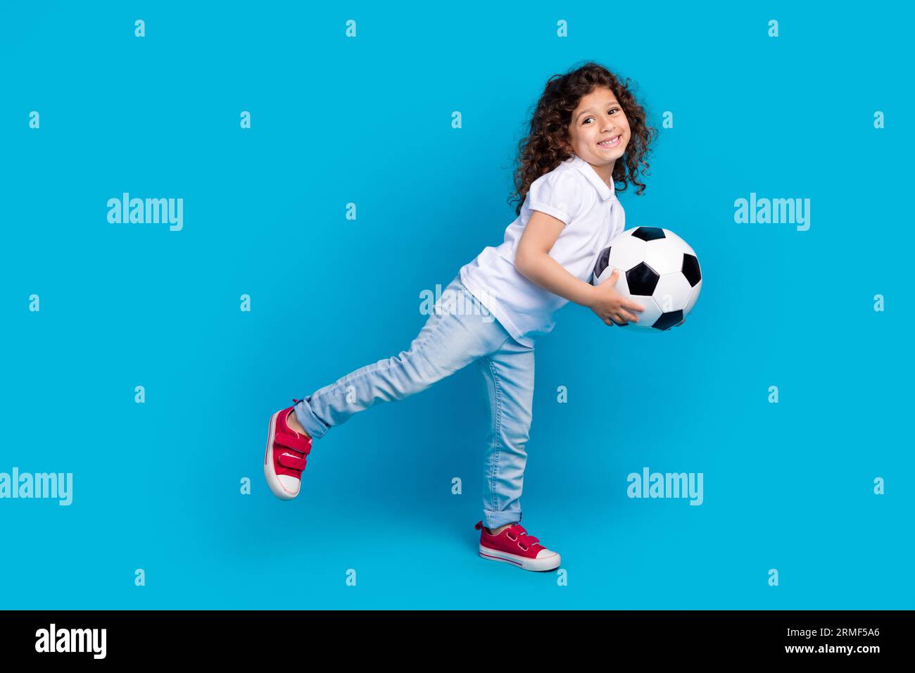 Photo of sporty kid girl playing football with friends isolated blue ...