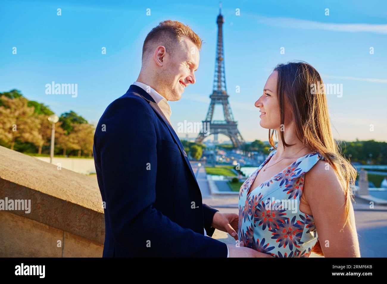 Romantic couple together in Paris near the Eiffel tower looking at each ...