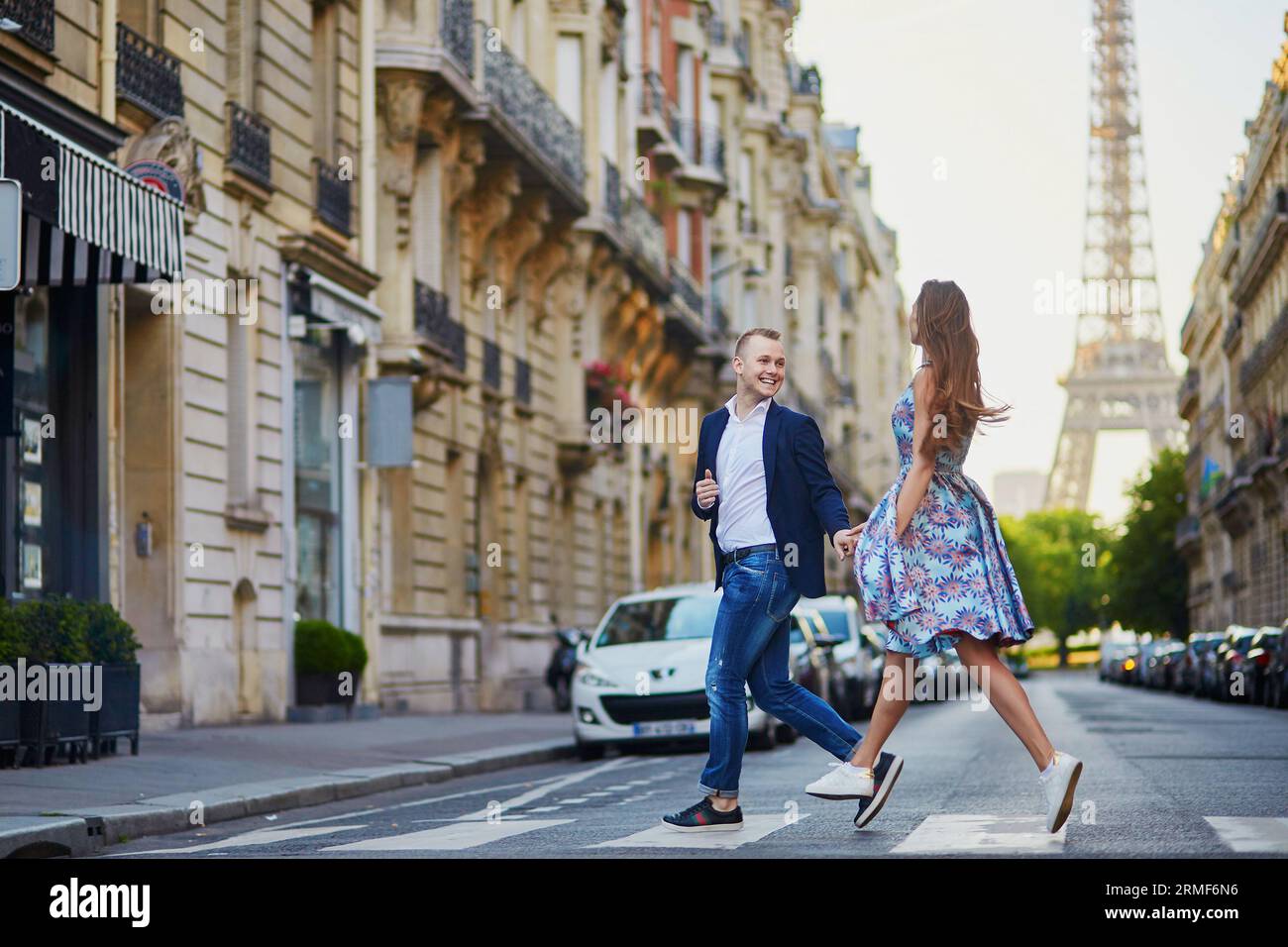 Romantic couple running across the street with Eiffel tower in ...