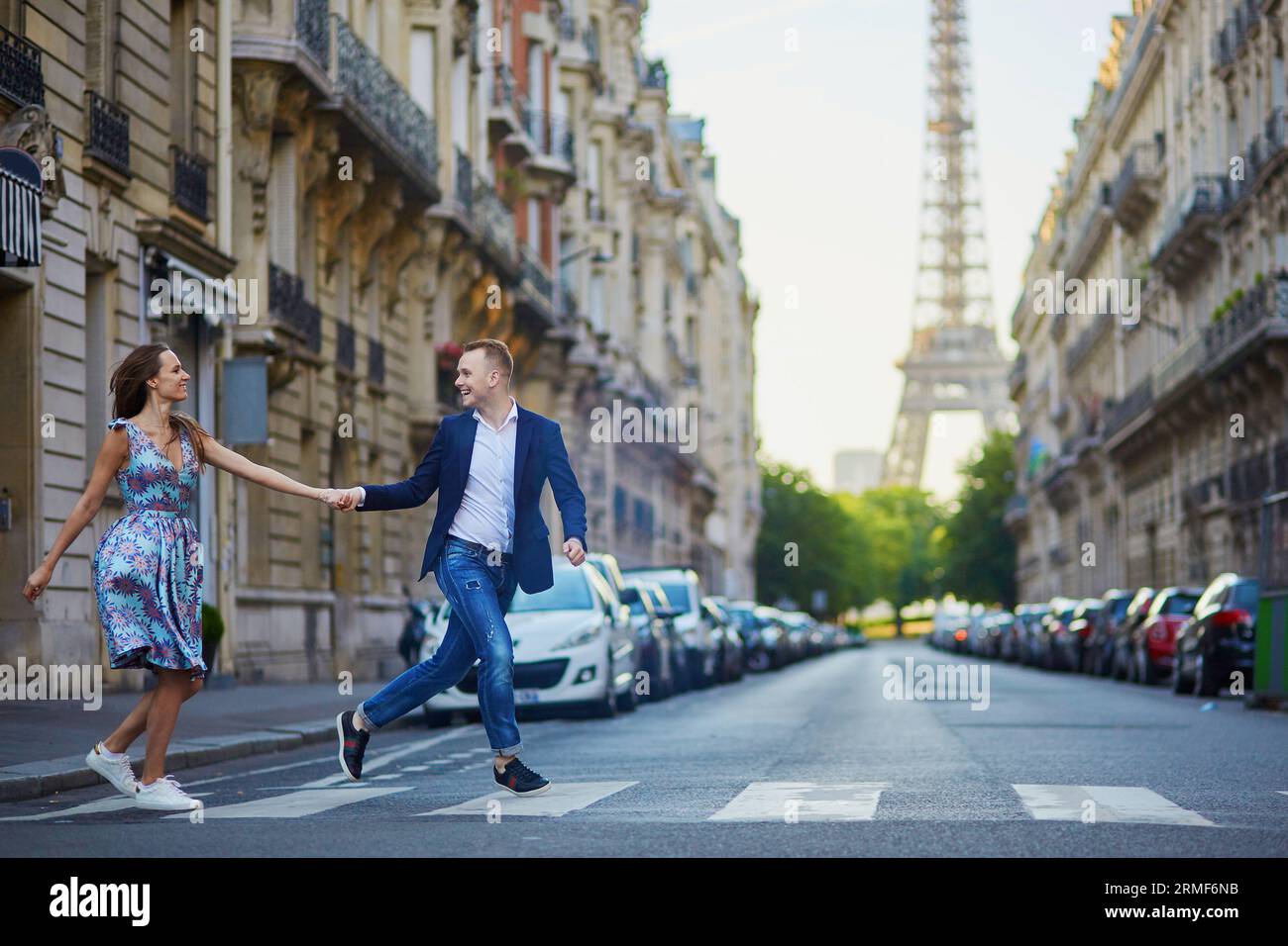Romantic couple running across the street with Eiffel tower in ...