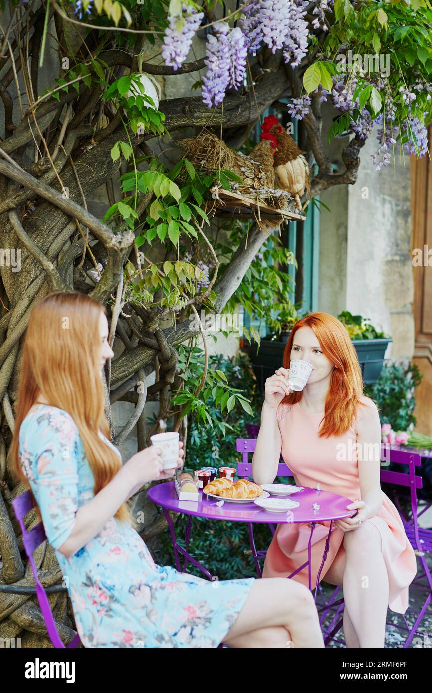 Two Parisian women drinking coffee together in an outdoor cafe with ...